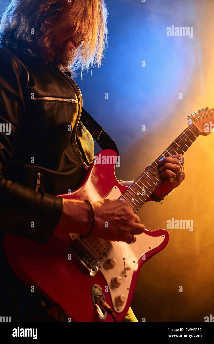 Ambient vertical portrait of long haired rock musician playing electric ...