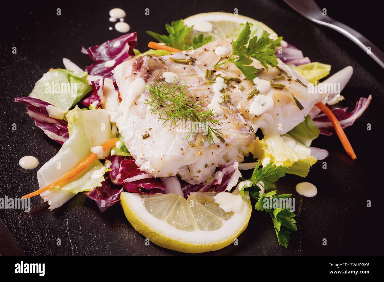 Grilled cod fillet with salad on black slate plate Stock Photo - Alamy