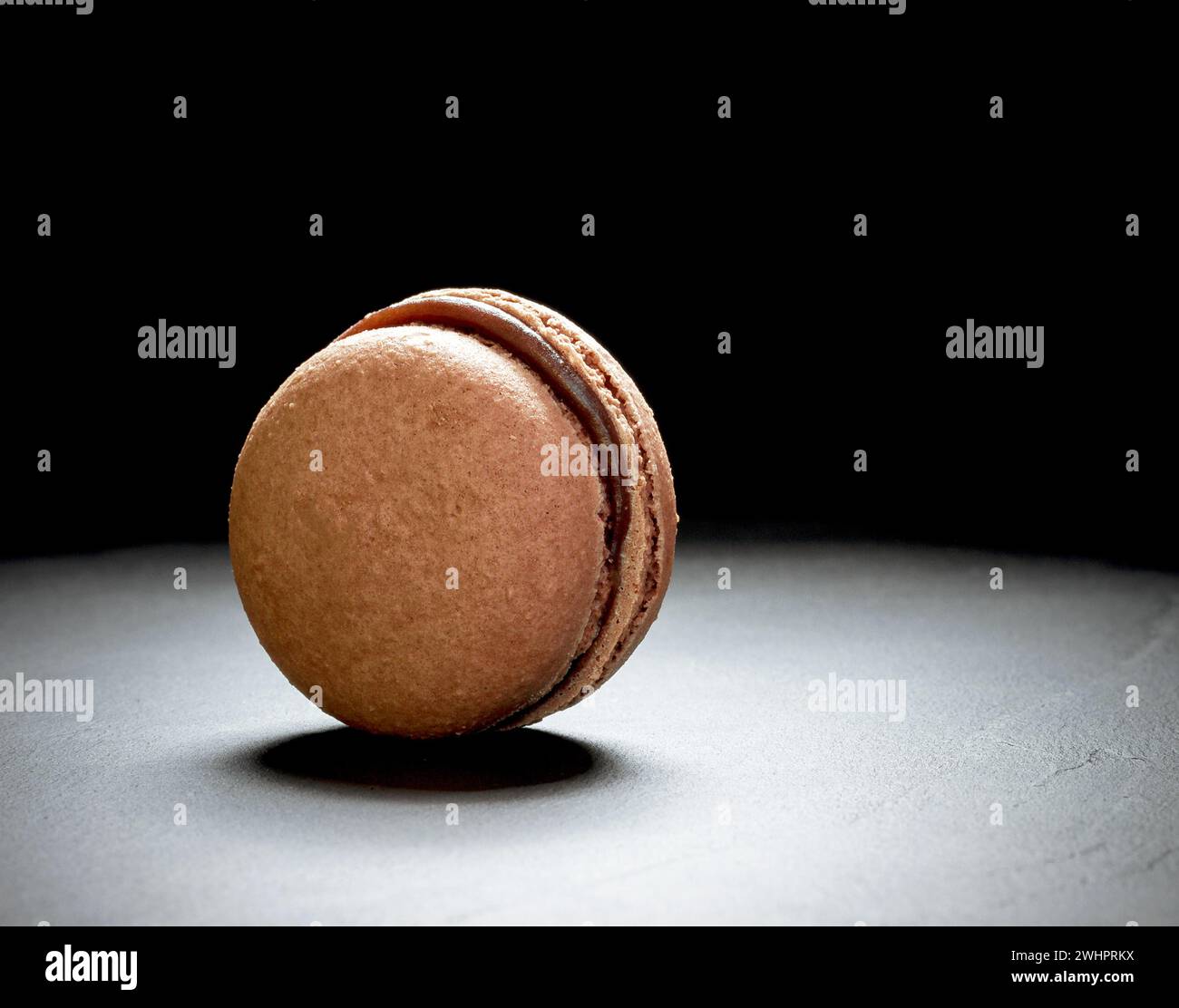 Chocolate macaron at the black background Stock Photo - Alamy