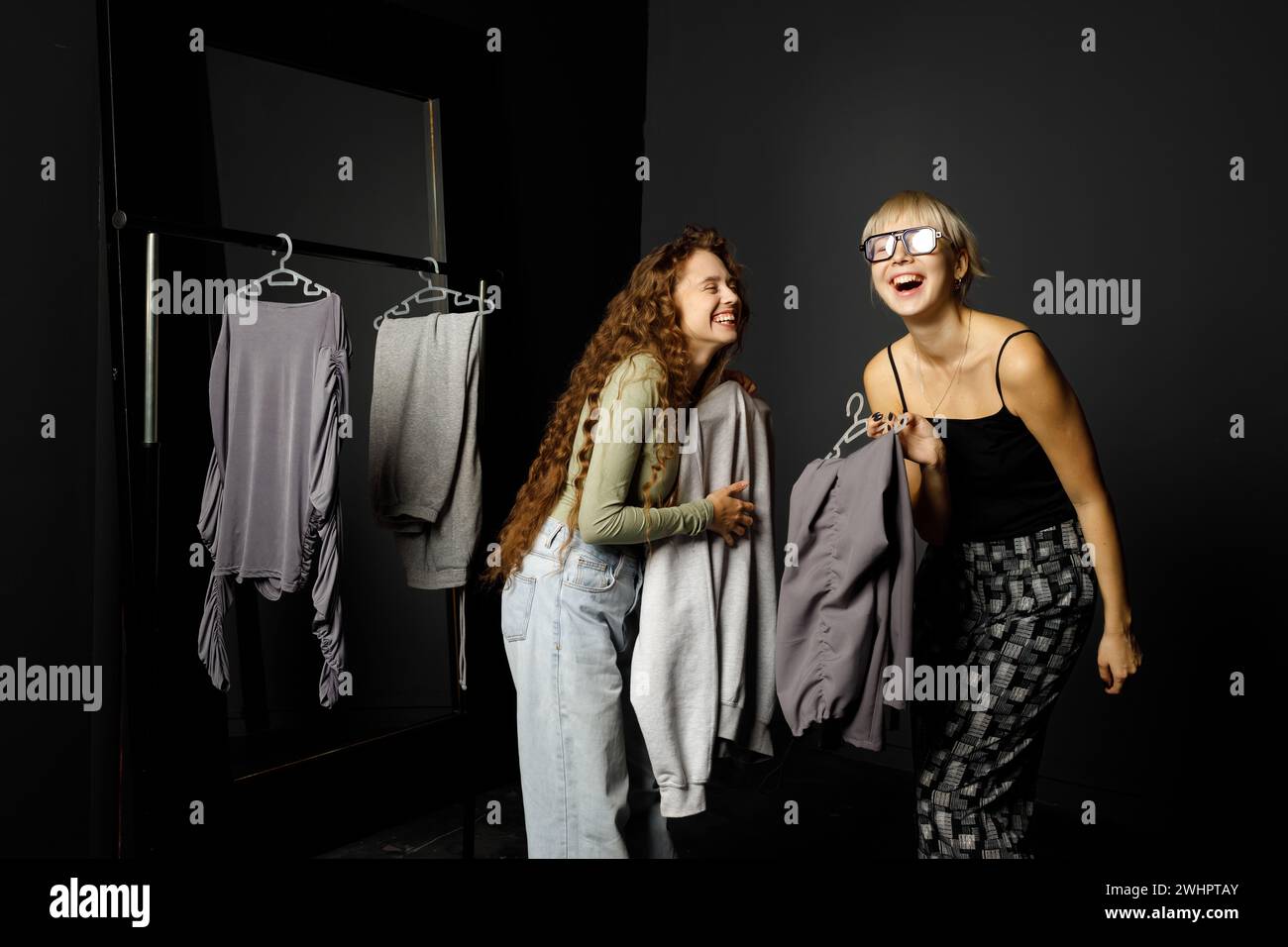 Beautiful young woman stylist designer helping choose clothes to ...