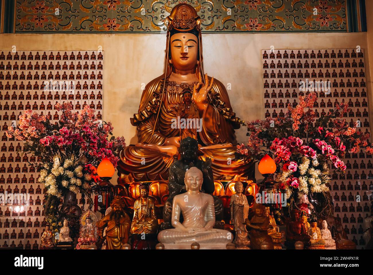 Lots of golden statues of the Thai gods with fresh flowers. Thai ...