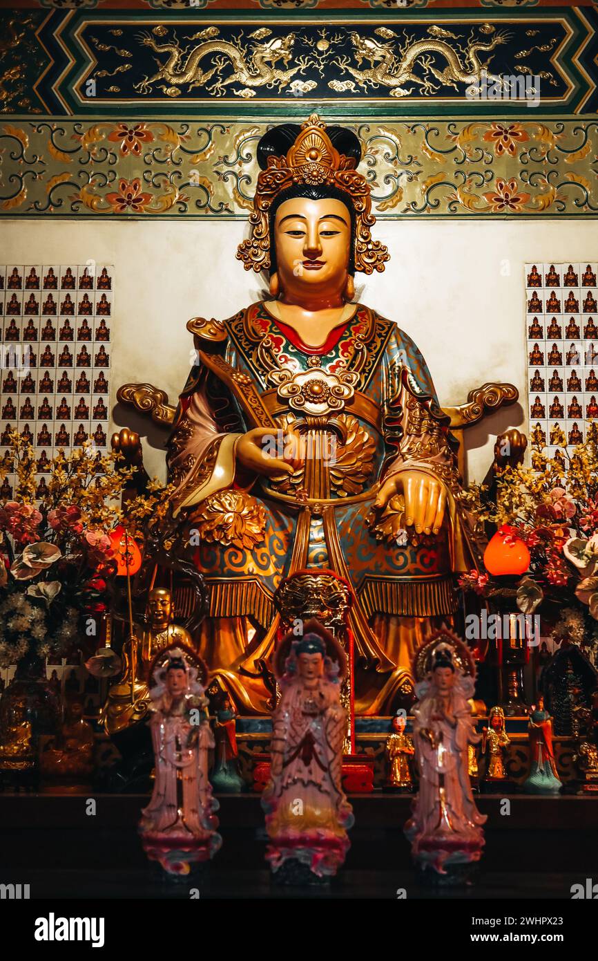 Lots of golden statues of the Thai gods with fresh flowers. Thai ...