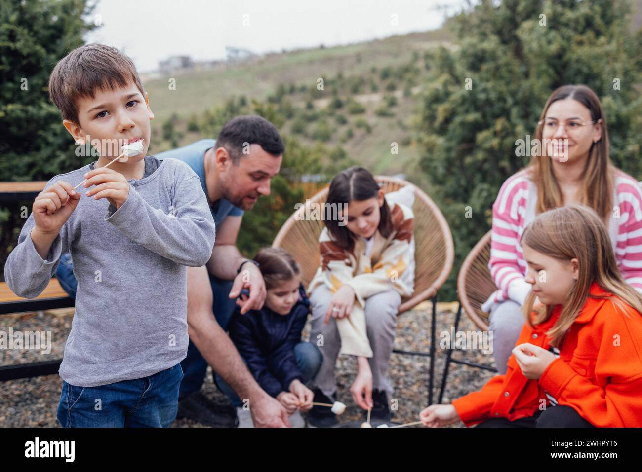Big happy family roasting mashmallows outdoors. Little cute boy eating ...