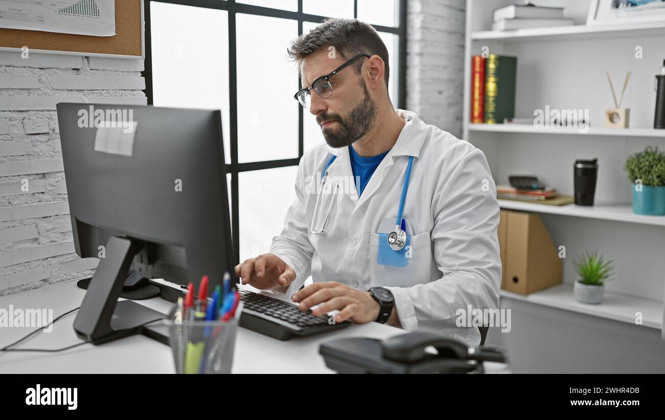 Bearded young hispanic man doctor hard at work, using his computer ...