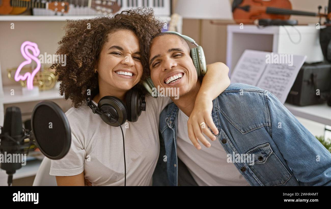 Smiling musicians at music studio, wearing headphones and hugging each ...