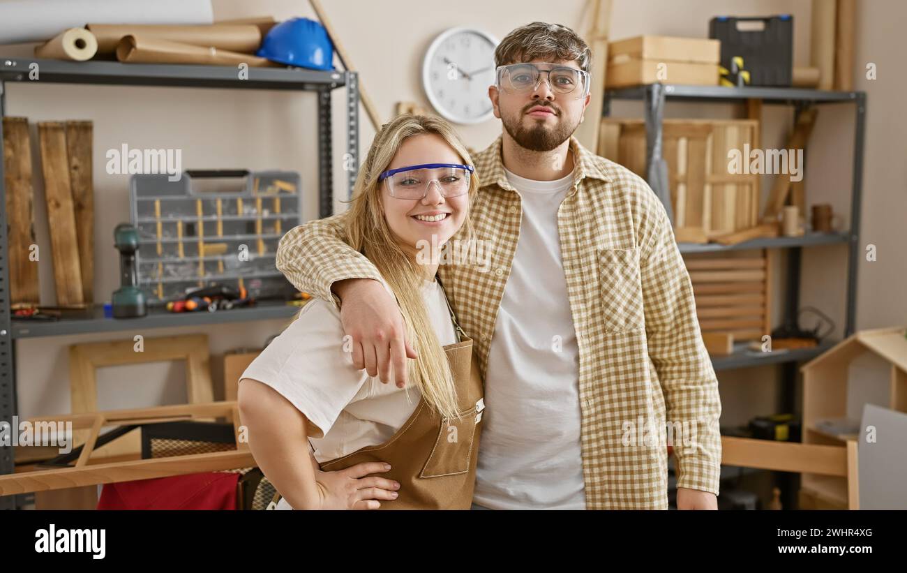 Confident woman and man carpenters posing in a well-equipped ...