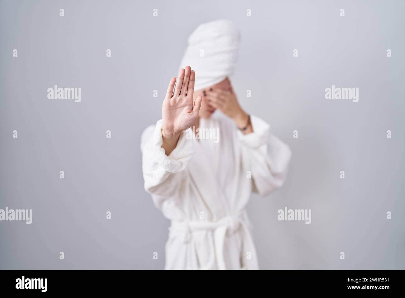 Blonde caucasian woman wearing bathrobe covering eyes with hands and ...
