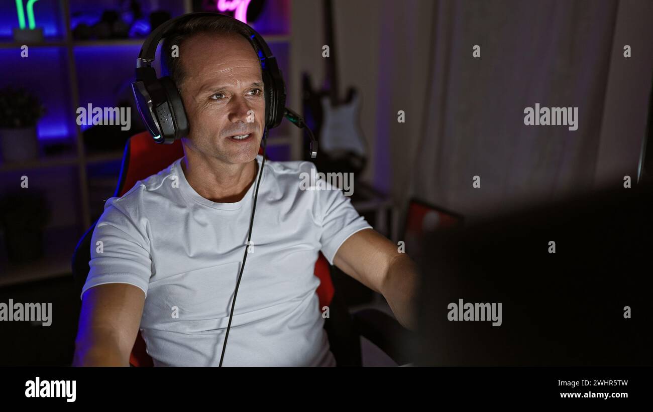 Handsome middle age man streaming video game at night, sitting ...
