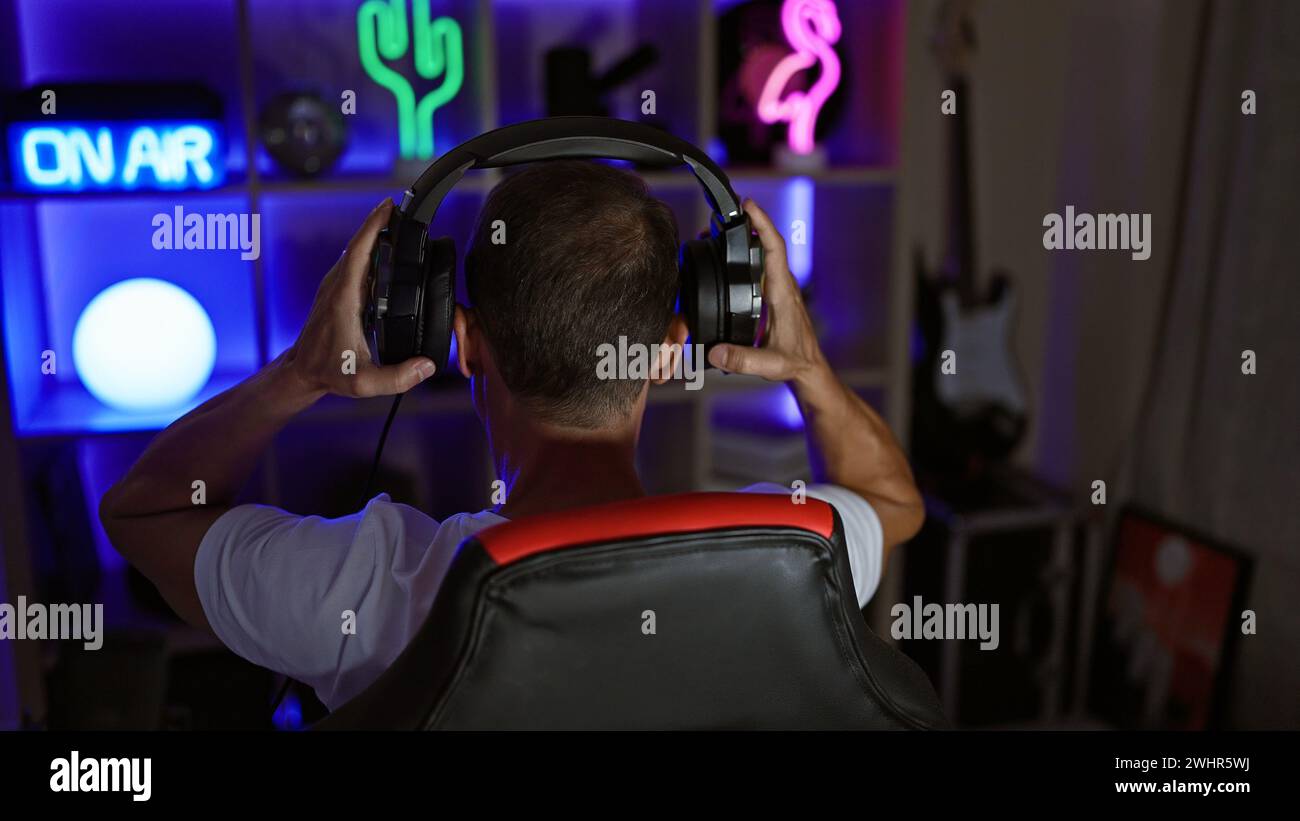 Middle-aged gamer man, streamer streaming live in his dark gaming room ...