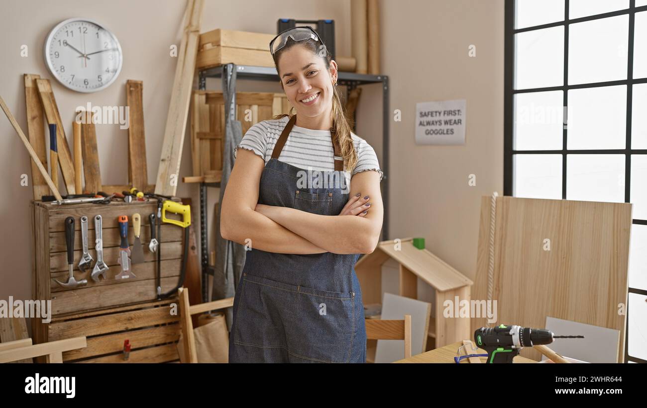 Confident woman in denim apron stands arms crossed in a well-equipped ...