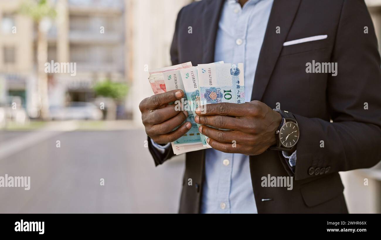 African man in suit counting chinese yuan outdoors in an urban setting ...