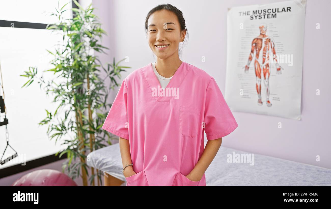 Asian woman healthcare professional in scrubs stands in a clinic with ...