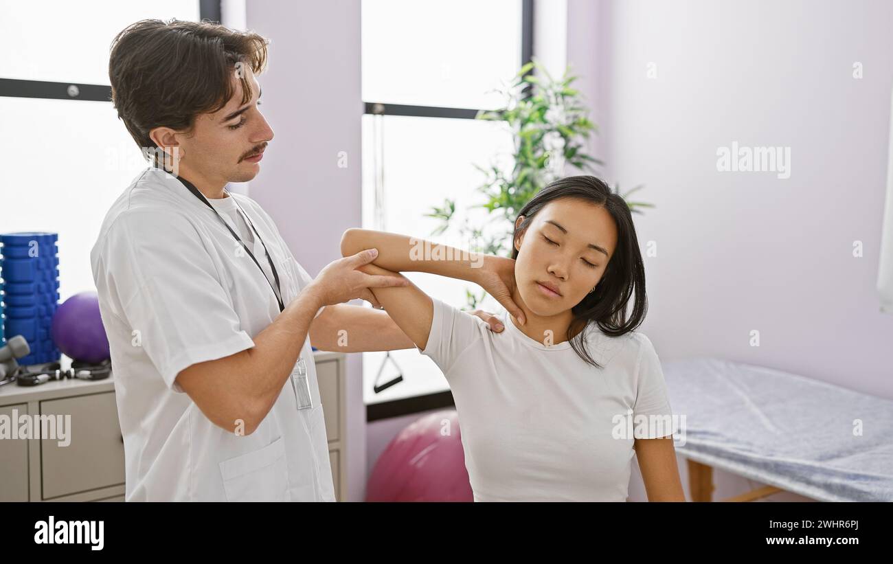 A Male Physiotherapist Assists A Female Patient With Arm Rehabilitation
