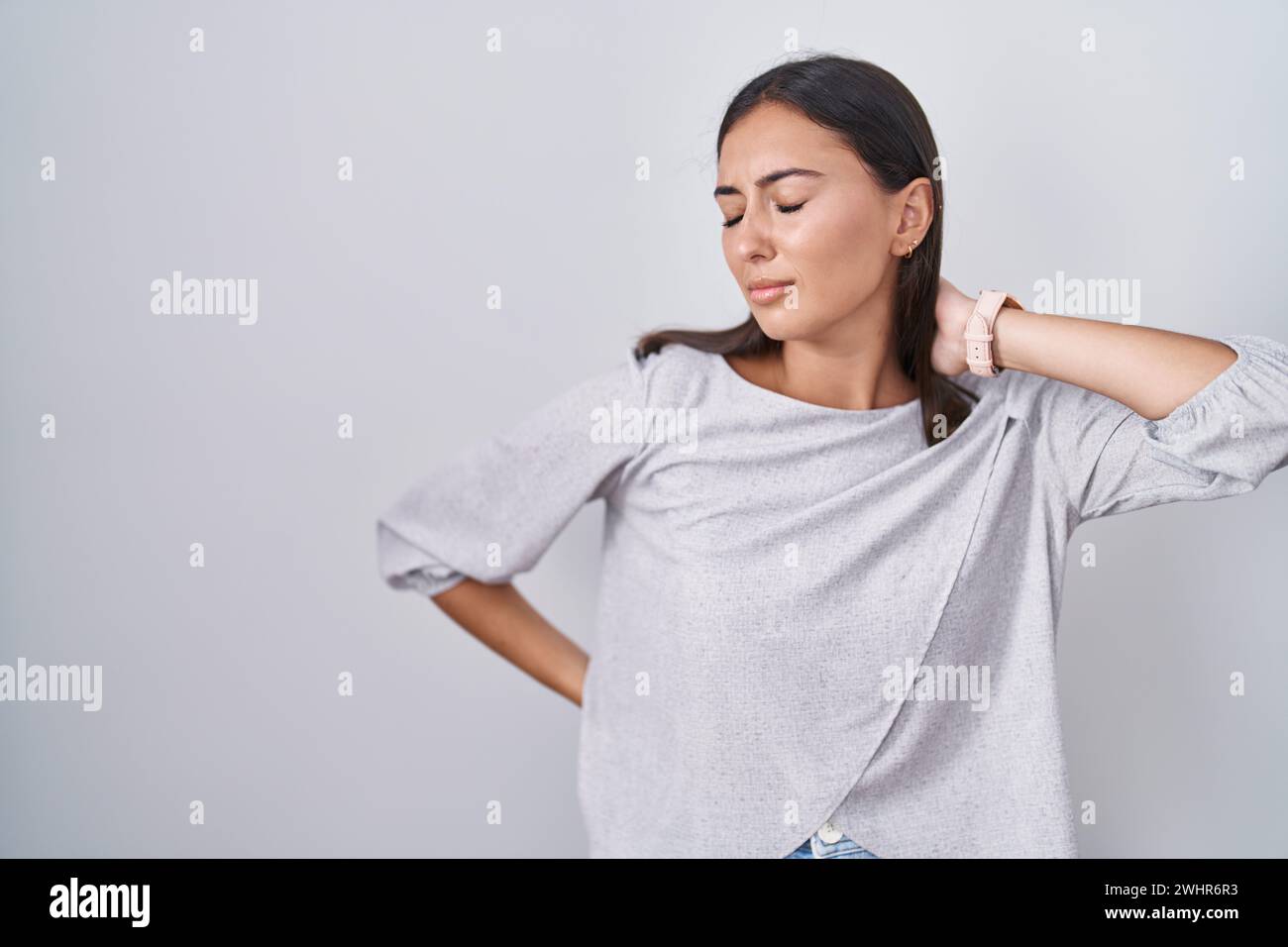 Young hispanic woman standing over white background suffering of neck ...