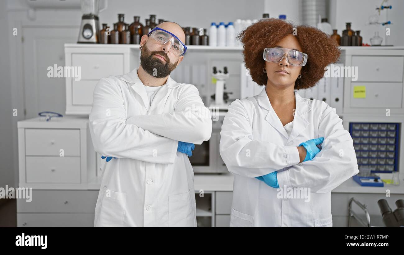 Two serious-faced scientists, arms crossed, standing together in a high ...