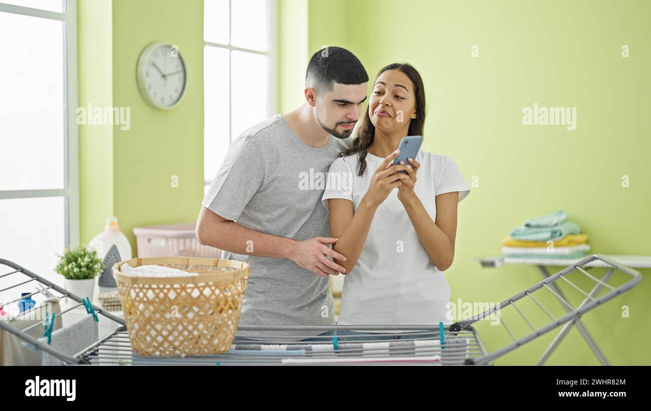 Smiling beautiful couple engrossed in smartphone, laughing together ...