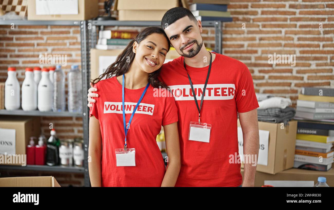 Smiling man and woman volunteers enjoy hugging each other, standing in ...