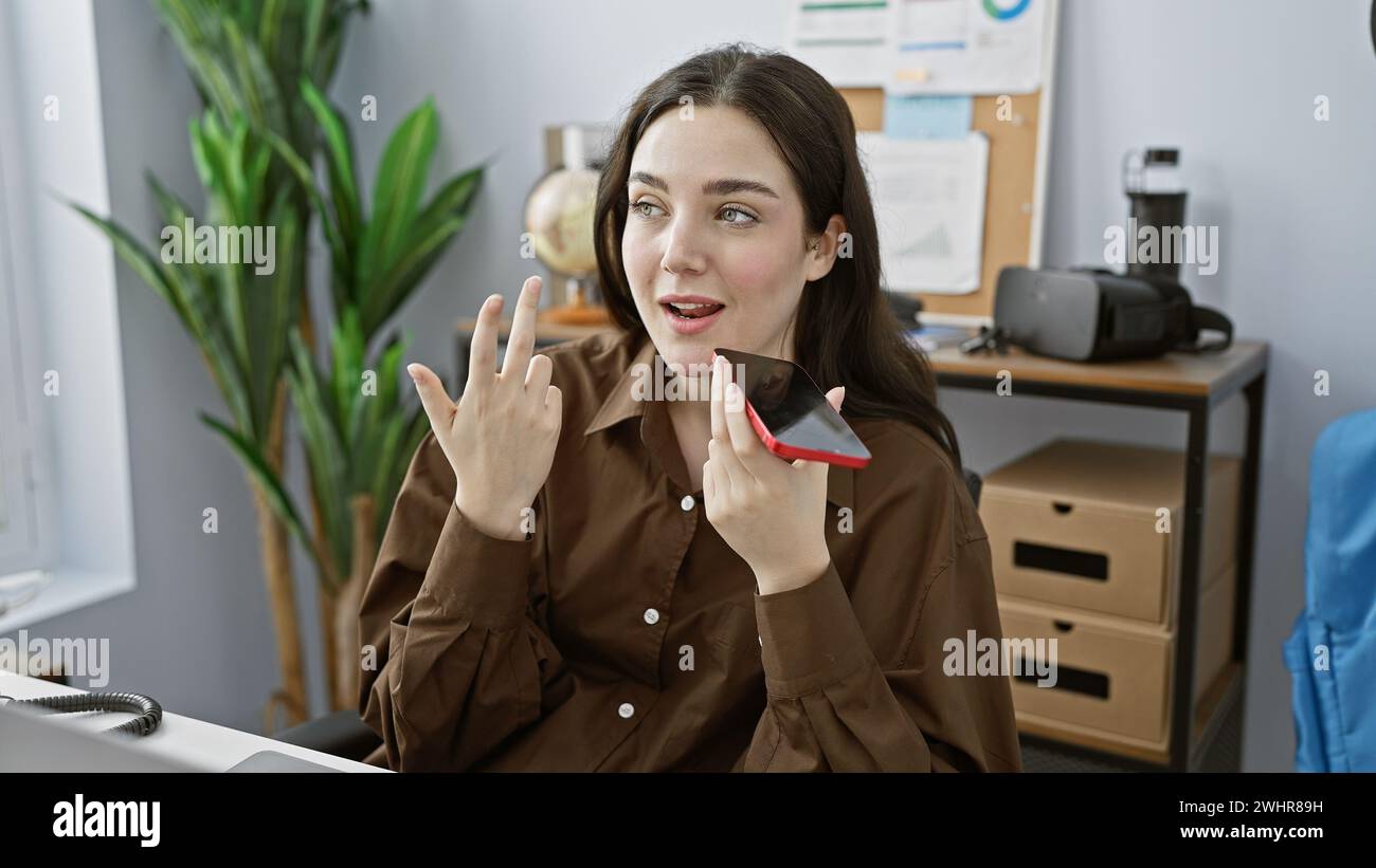 A young caucasian woman records a voice message in a modern office ...
