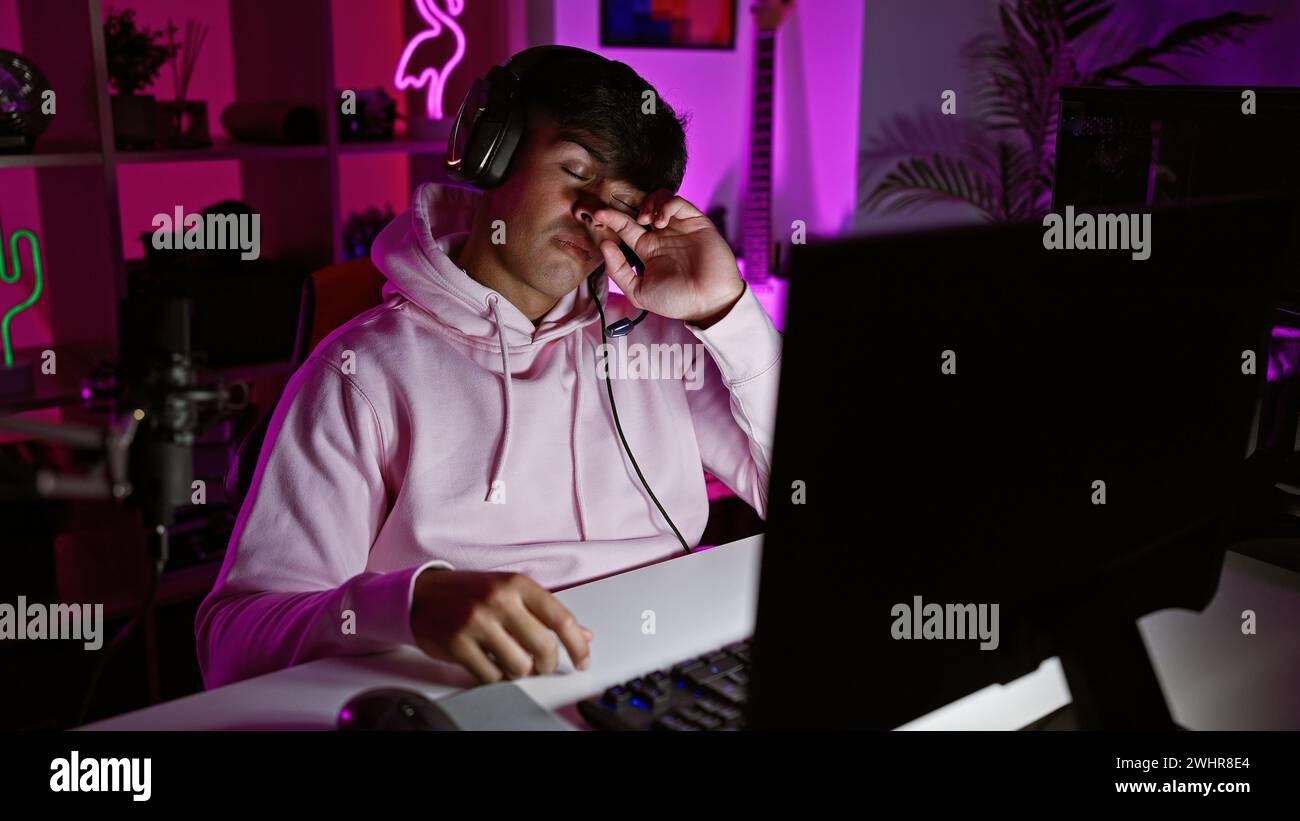 Tired young hispanic man streamer, late night gaming session in dark ...