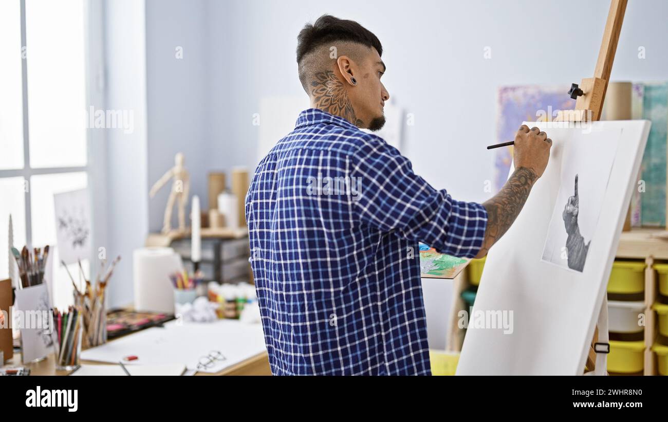 Passionate, tattooed latin man artist immersed in drawing his portrait ...