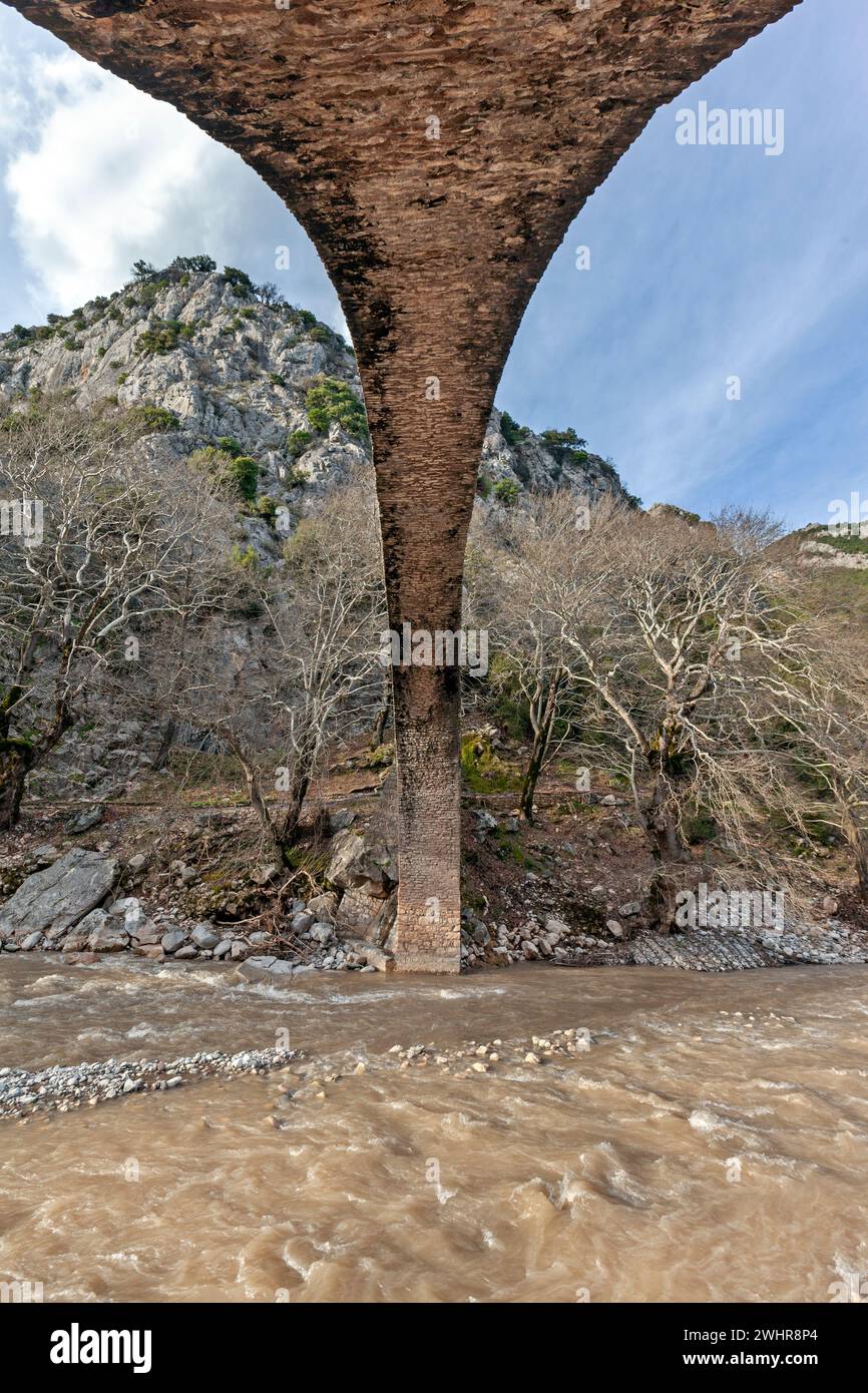 Below the arch of the stone bridge over Portaikos river, an old ...