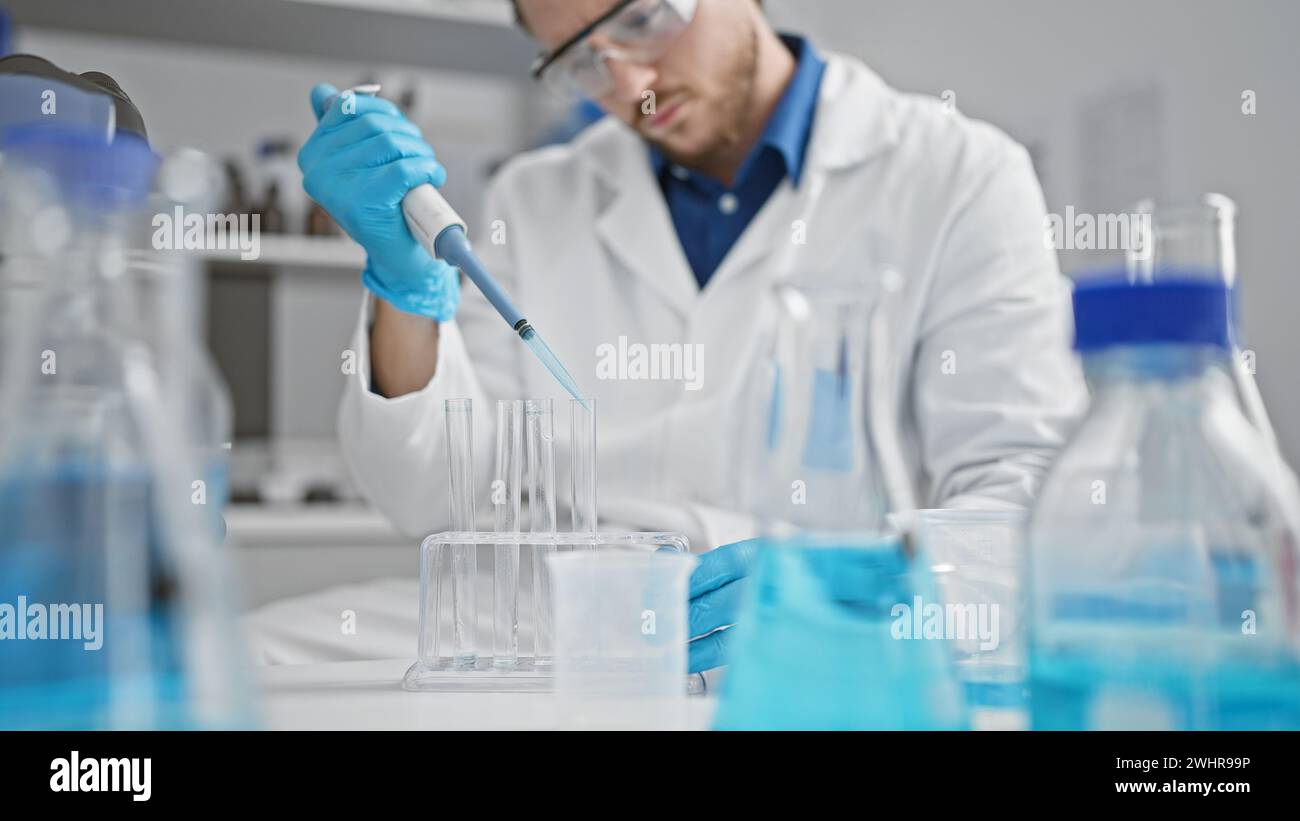 Young hispanic man scientist pouring liquid on test tube at laboratory ...