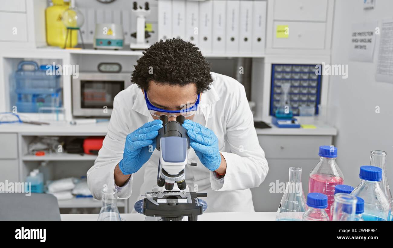 African american male scientist analyzing samples using a microscope in a laboratory setting ...