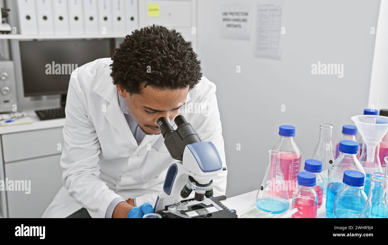 African american man analyzes samples using a microscope in a modern ...