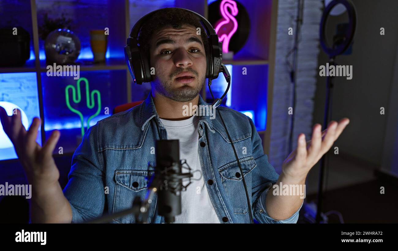 A perplexed young man wearing headphones in a vibrant gaming room at ...