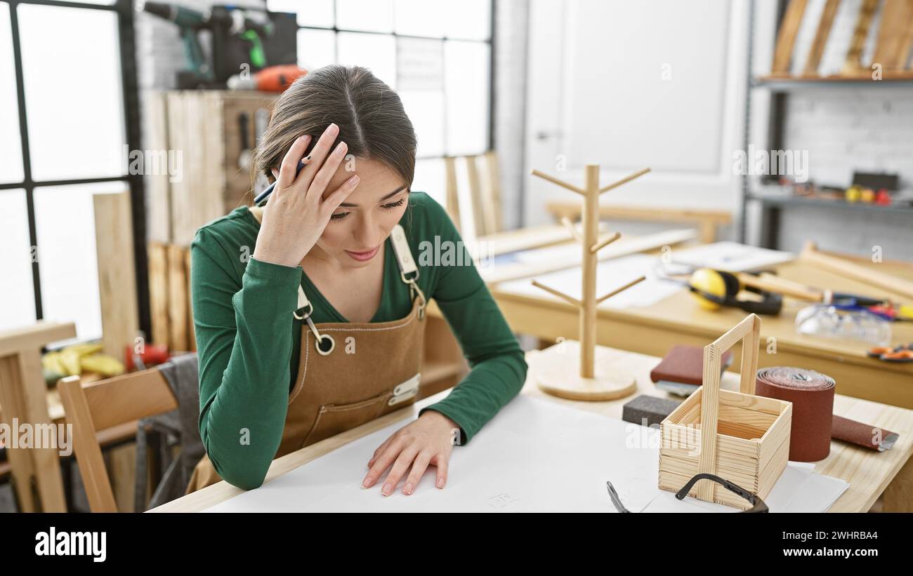 A frustrated woman artisan in a workshop with tools and wooden objects ...