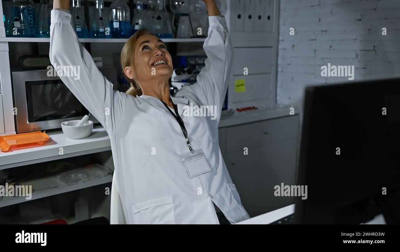 A joyful blonde woman stretching in a modern laboratory setting ...