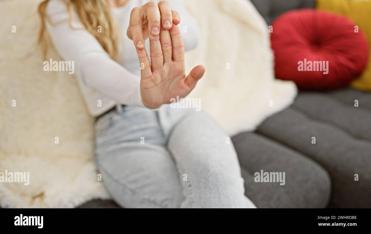 A young blonde woman stretches her hand in a cozy living room ...
