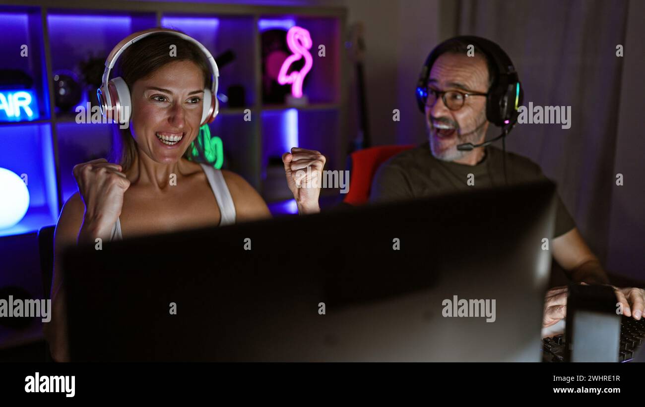 Exciting night in gaming room, two cheerful gamers, father and daughter ...