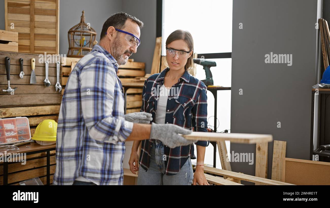 Two dedicated carpenters speak serious shop, holding lumber plank in ...