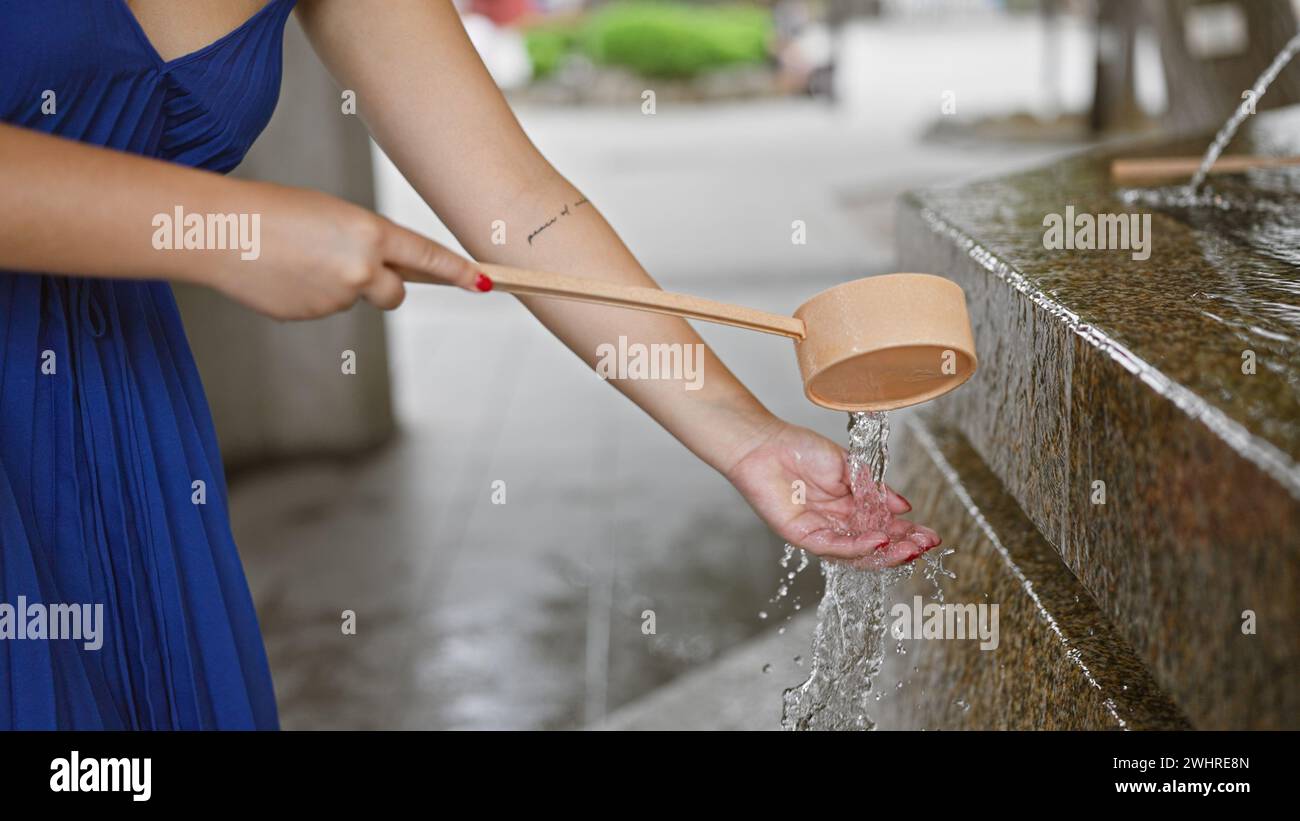 Young woman immersed in traditional ritual, washing hands in purifying ...