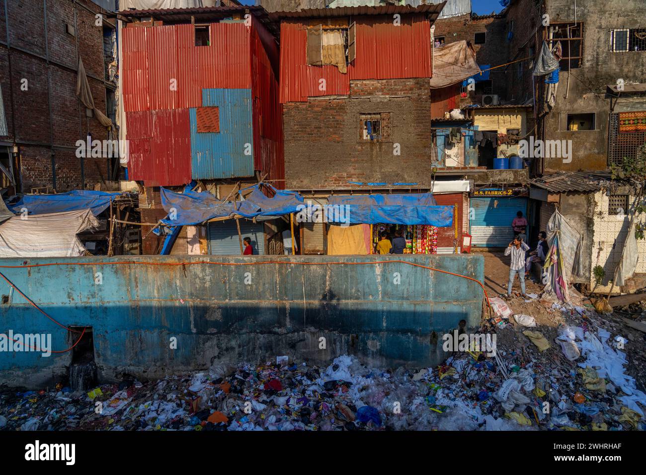 A man uses a mobile phone as he stands next to plastic refuse and other ...
