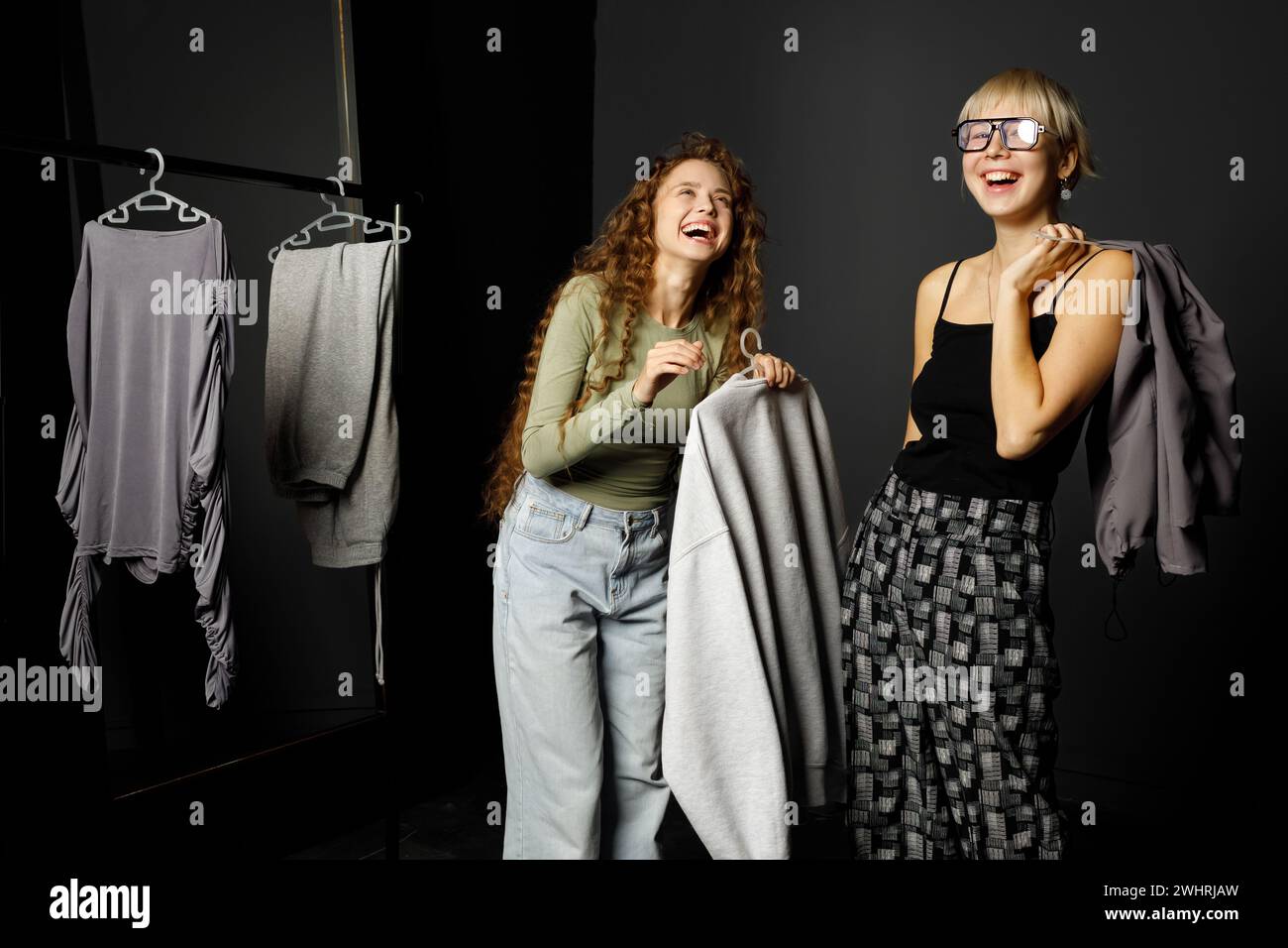 Beautiful young woman stylist designer helping choose clothes to ...
