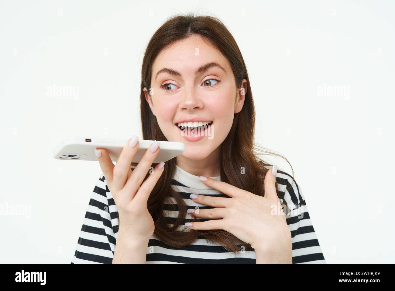 Image of cute brunette woman talking into speakerphone, holding mobile ...