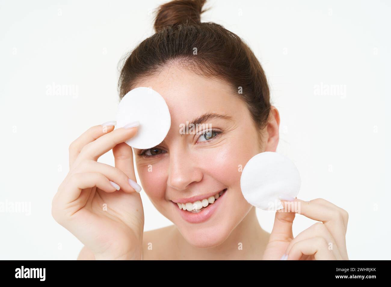 Beauty and cosmetics. Young smiling woman washing her face with cotton ...