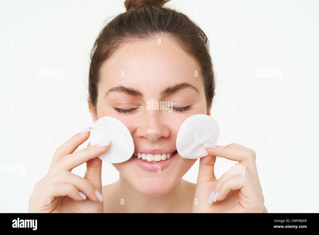 Image of young woman taking off her makeup with cotton pads, using ...
