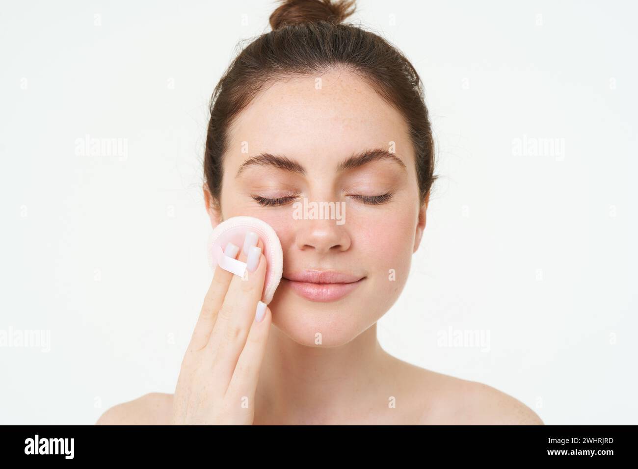 Image of young woman taking off her makeup with cotton pads, using ...