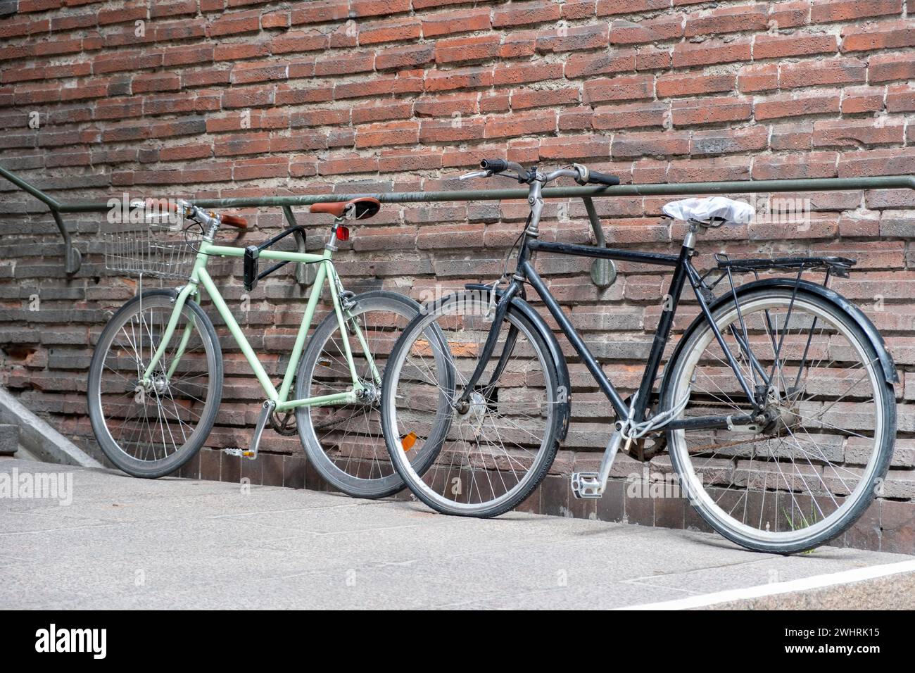 Bicycle locked and parked at brick wall building railing background ...
