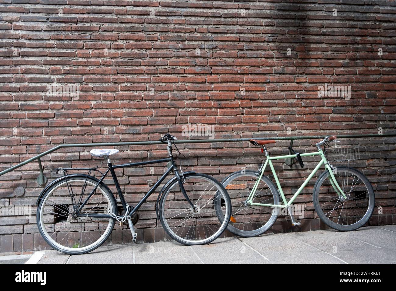 Bicycle locked and parked at empty brick wall building railing ...