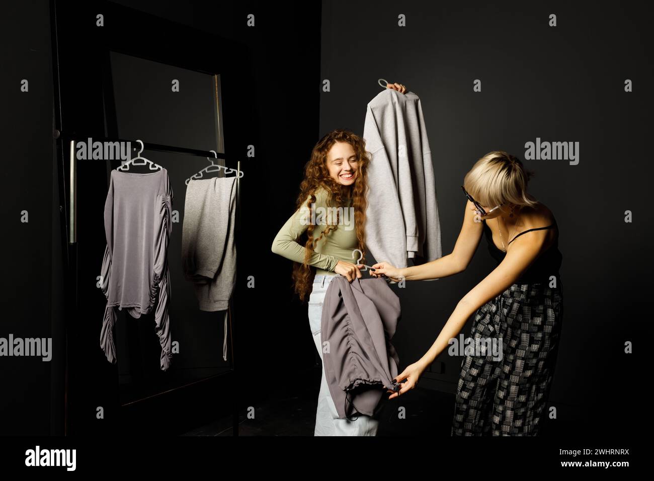 Beautiful young woman stylist designer helping choose clothes to ...