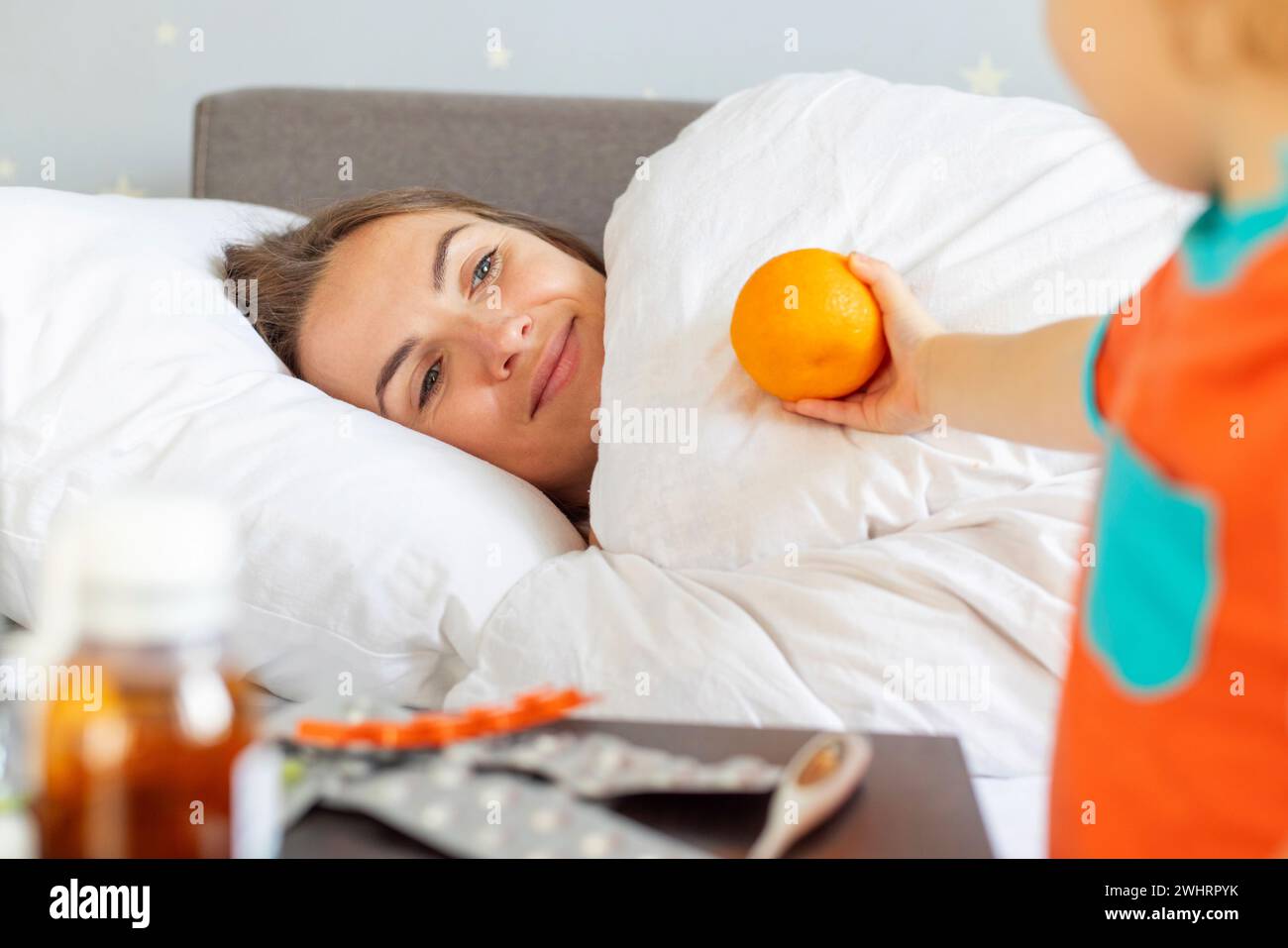 Child Offering Orange to Sick Mother in Bed Stock Photo - Alamy