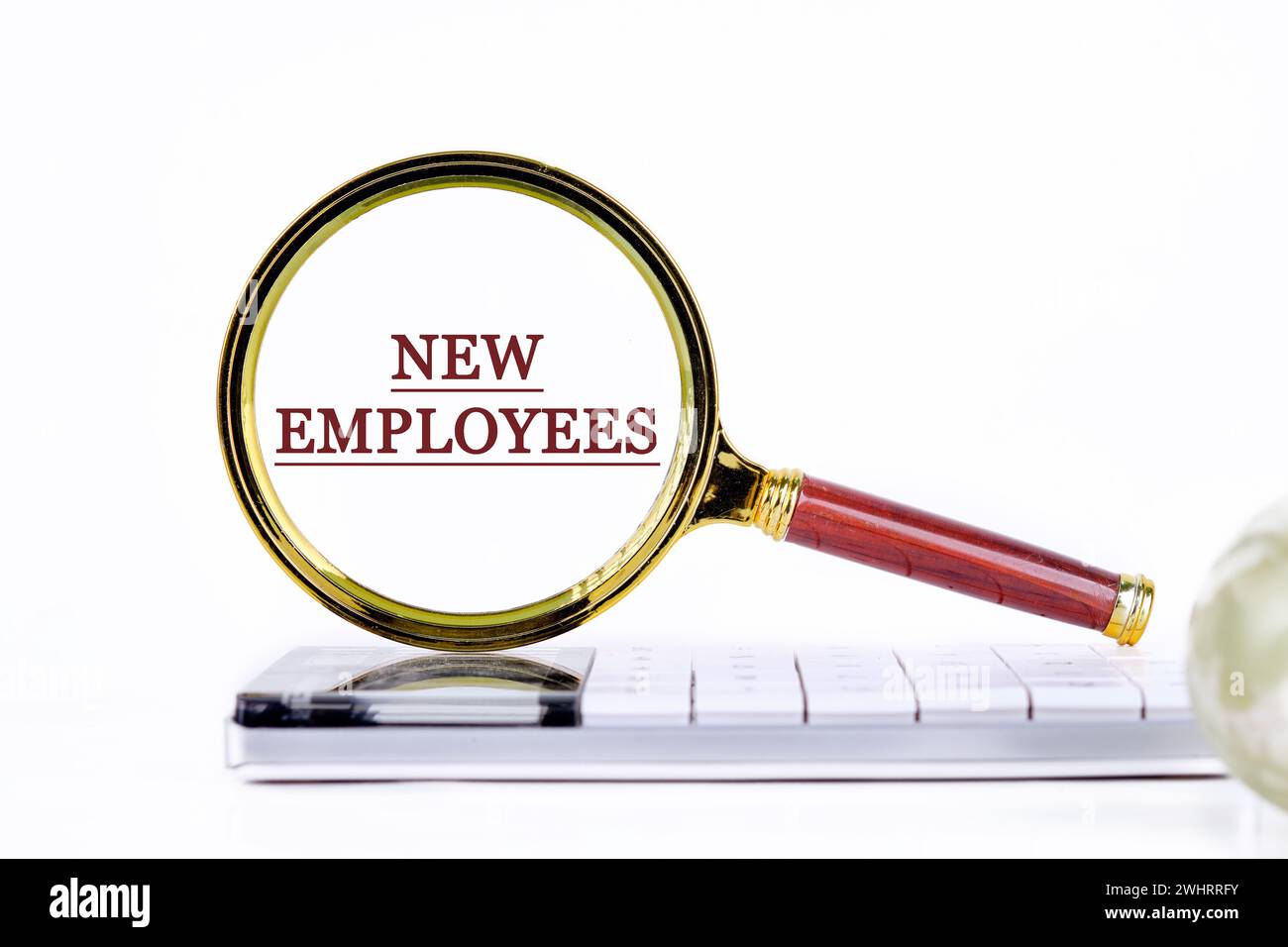 NEW EMPLOYEES Text written through a magnifying glass on a calculator ...