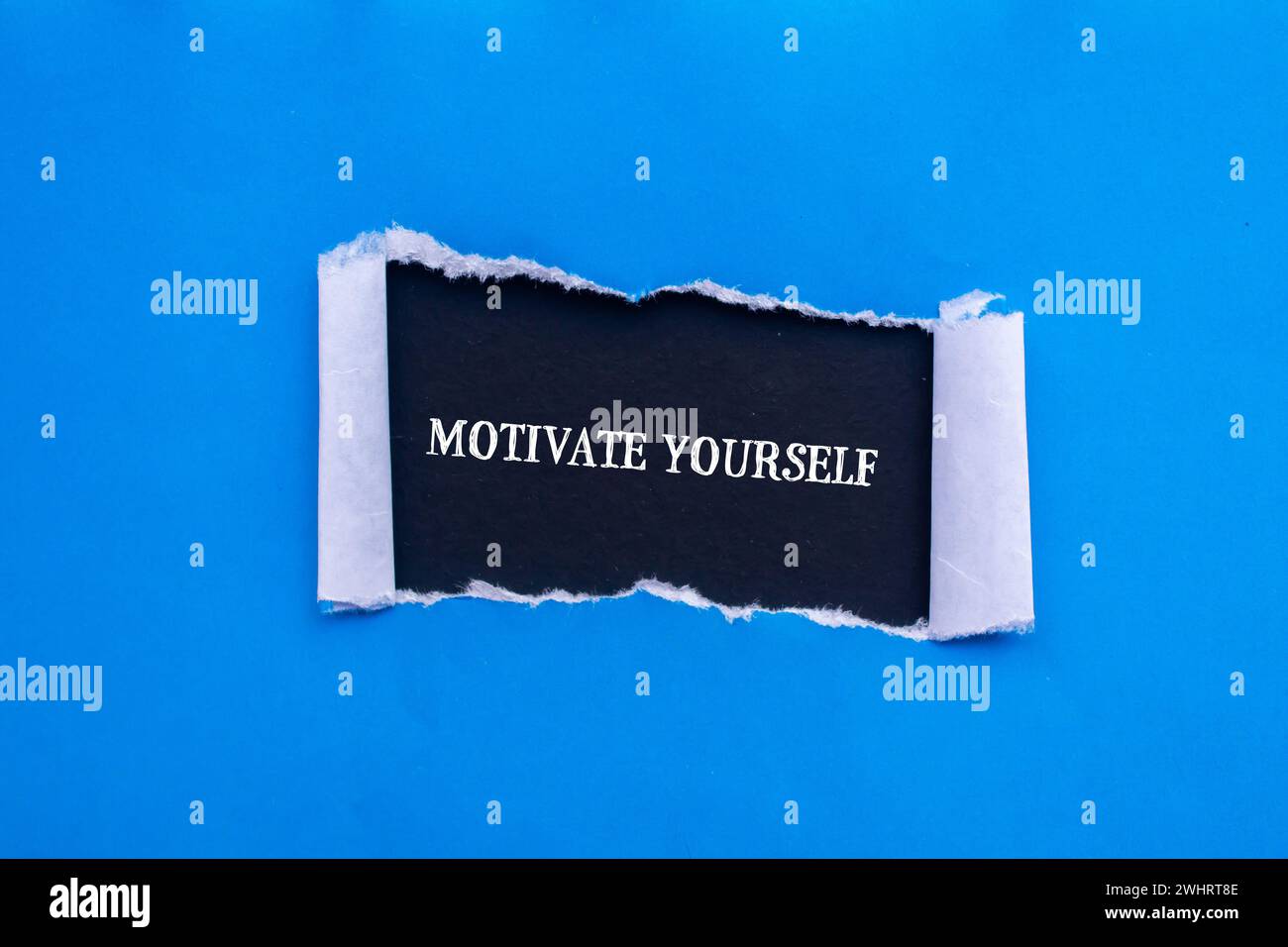 Motivate yourself words written on torn blue paper with black background. Conceptual symbol ...
