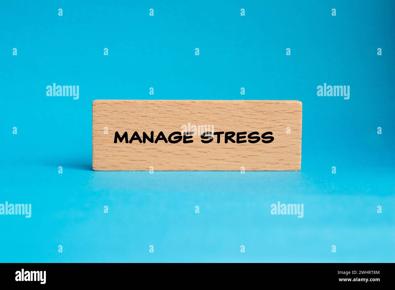 Manage stress lettering on wooden block with blue background ...