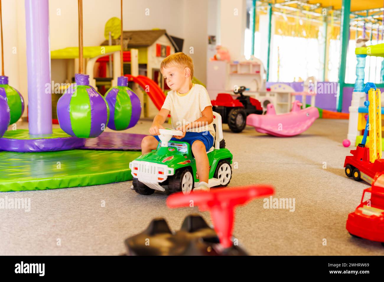 Young Boy Riding Toy Car at Indoor Playground Stock Photo - Alamy