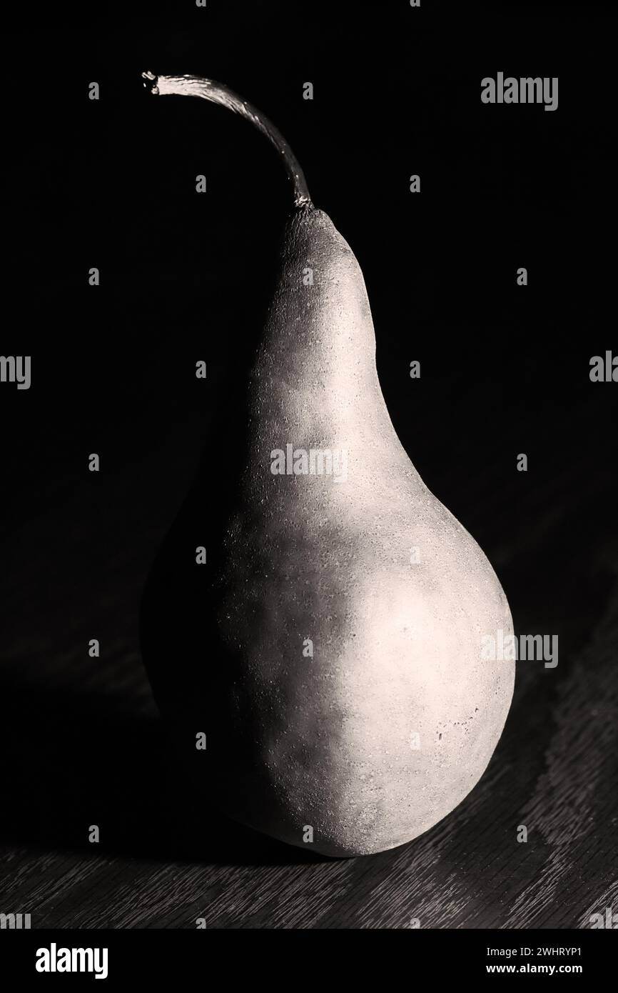 A Bosc pear (Pyrus communis 'Bosc') on a table with a dark background ...